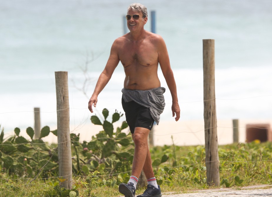 Sorridente, Alexandre Borges caminha na orla do Recreio dos Bandeirantes